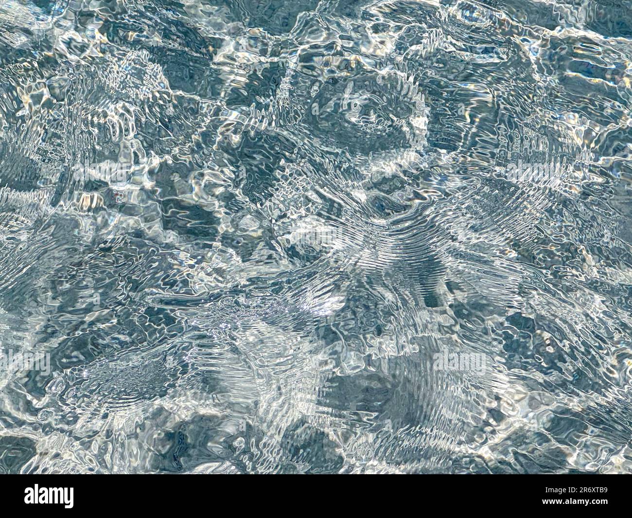 Light clear blue sea water background. Swimming pool surface with ...