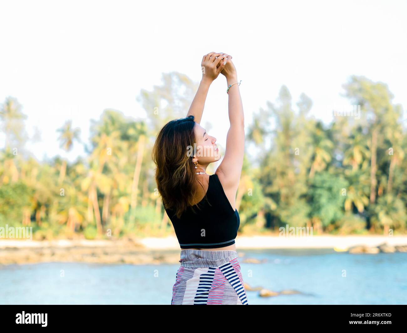 Back of Asian woman in black tank top closing eyes with relaxing raise ...