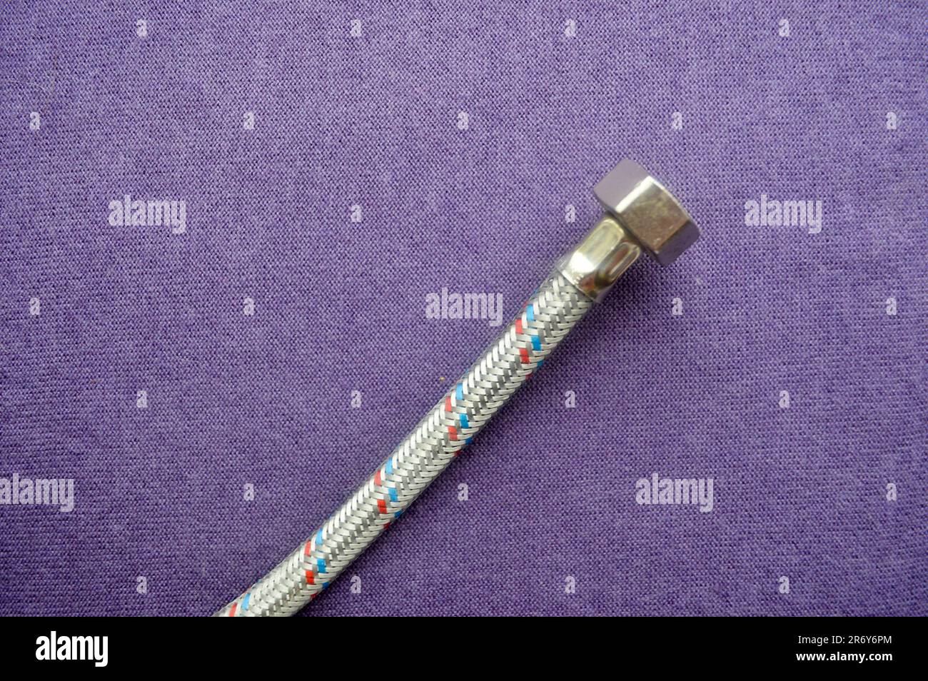 Threaded tap, reinforced, silver hose on a purple background. Plumbing ...