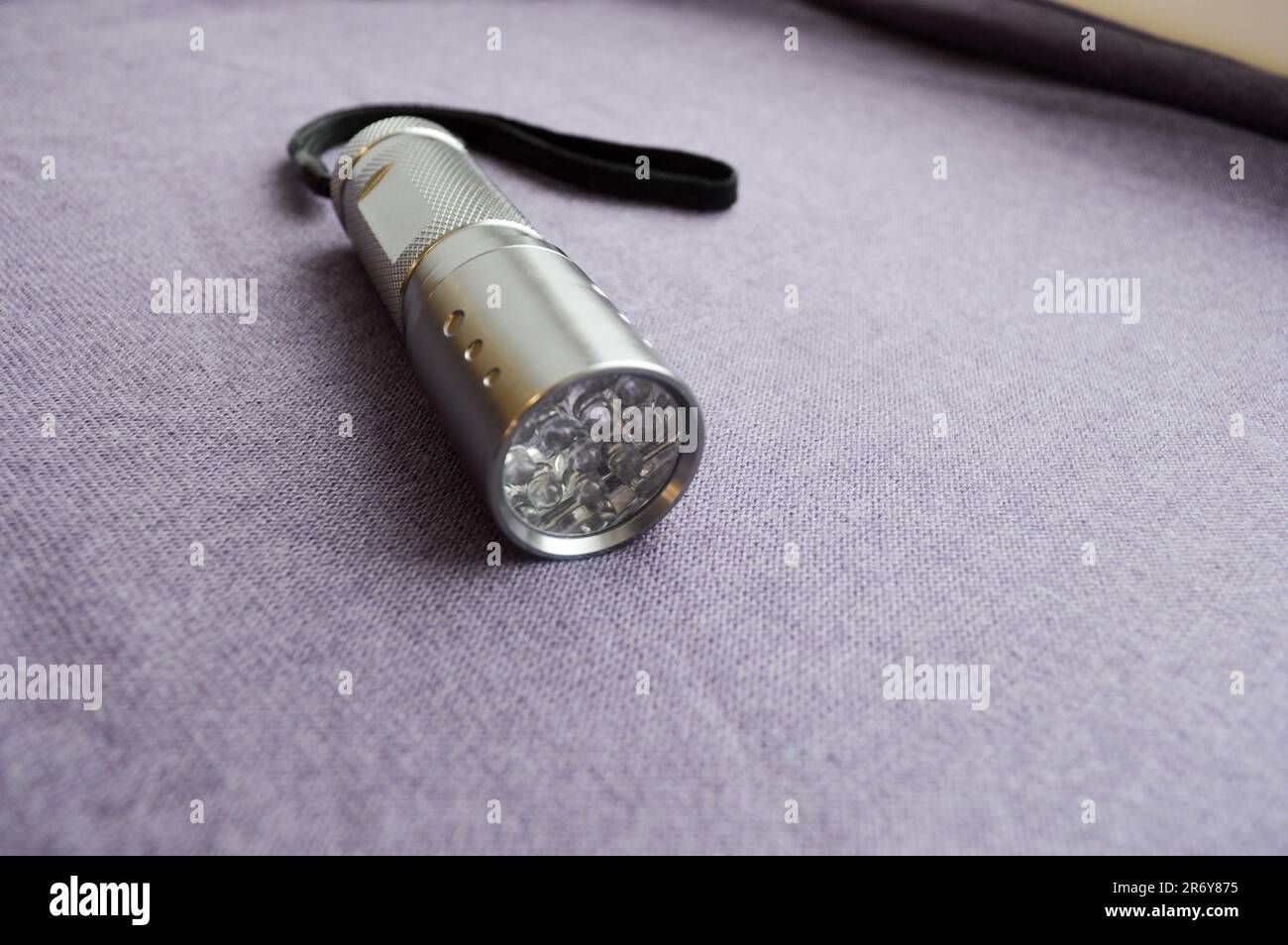 A metallic, shiny, made of stainless steel LED hand flashlight with a ...