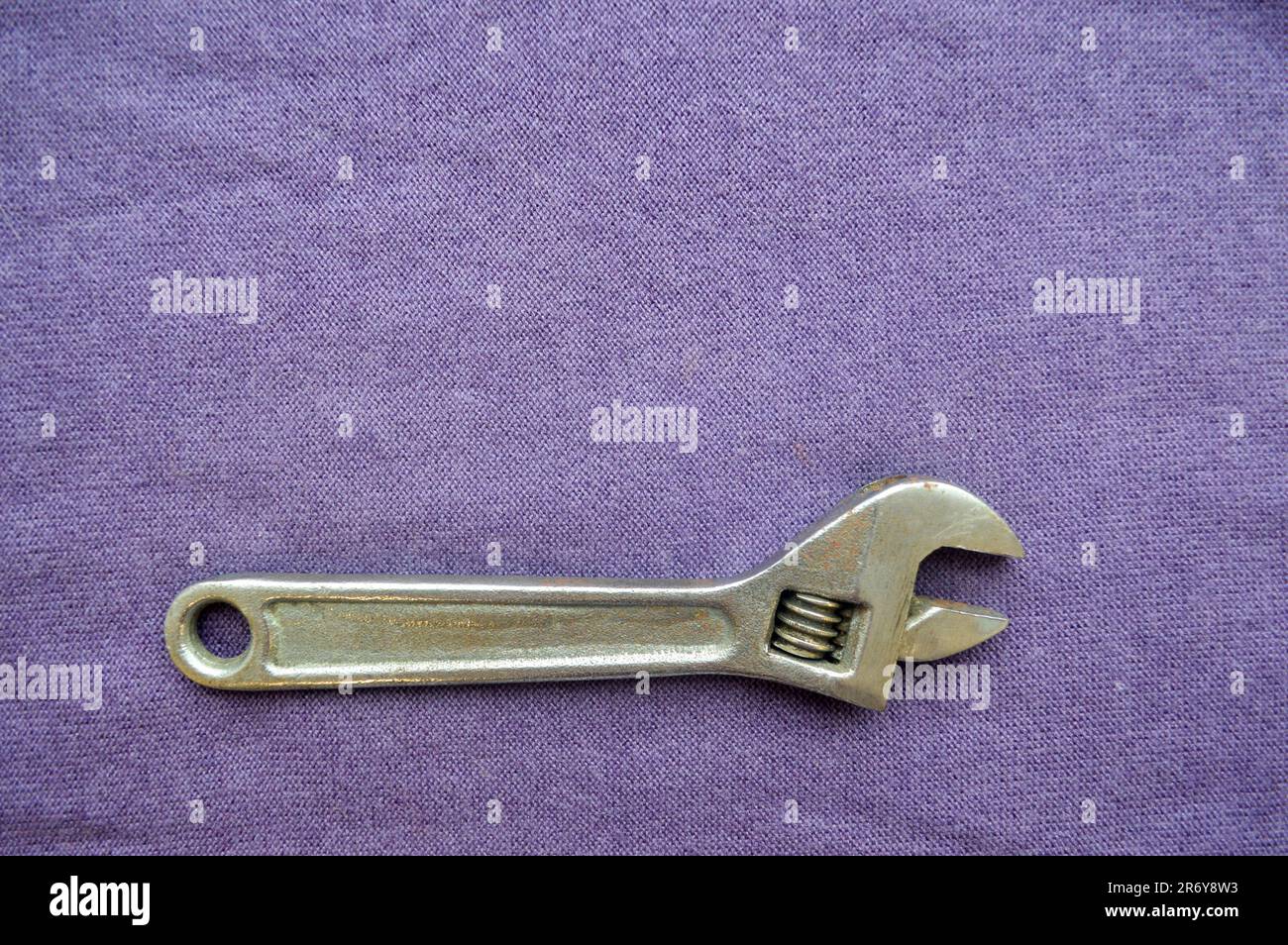 Metal, iron, shiny, adjustable wrench on a background of purple cloth ...
