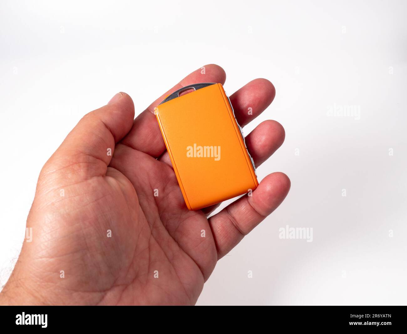 Modern wireless orange ignition key in hand on a white background ...