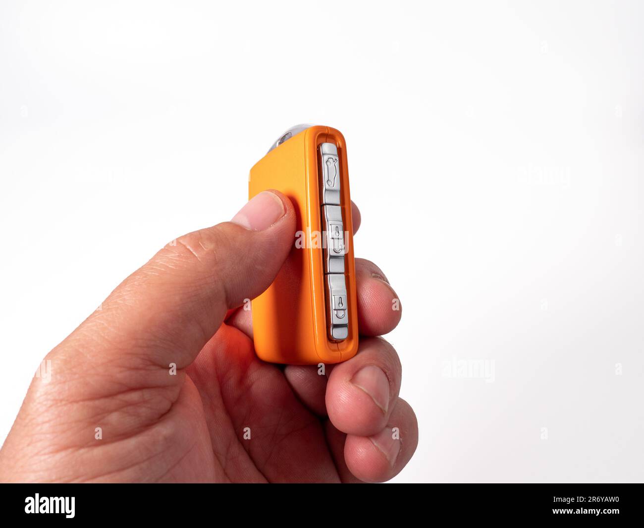 Modern wireless orange ignition key in hand on a white background ...