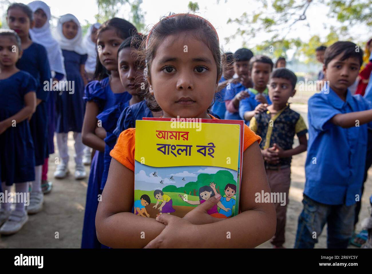 A primary school student holds new textbooks after receiving them for ...