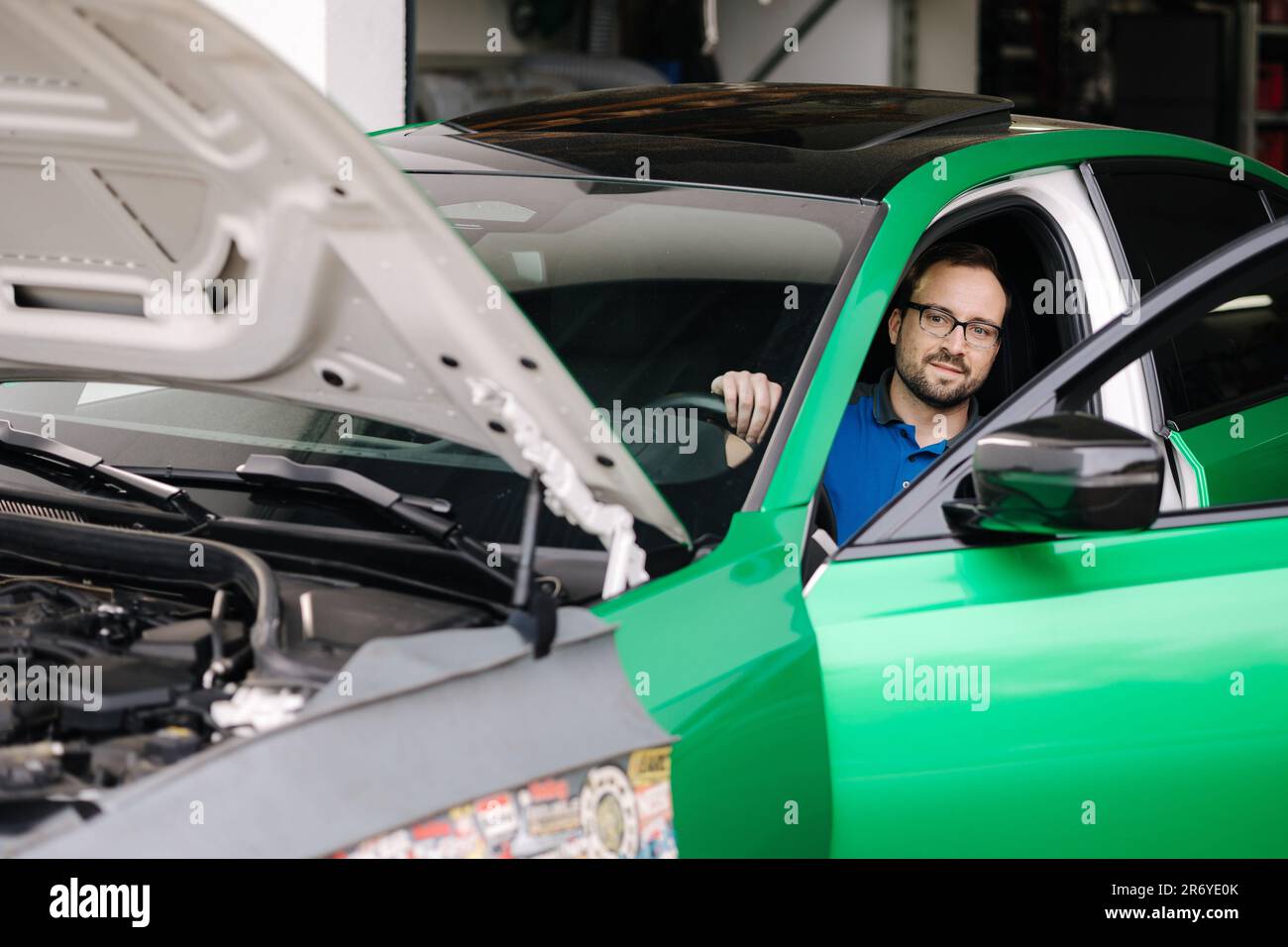 Photo of mechanic look into camera through an open car door. Man in ...