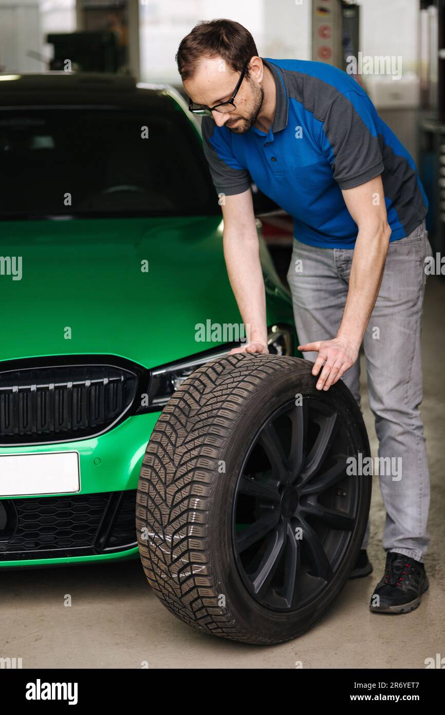 Technician rolls tire from car hi-res stock photography and images - Alamy