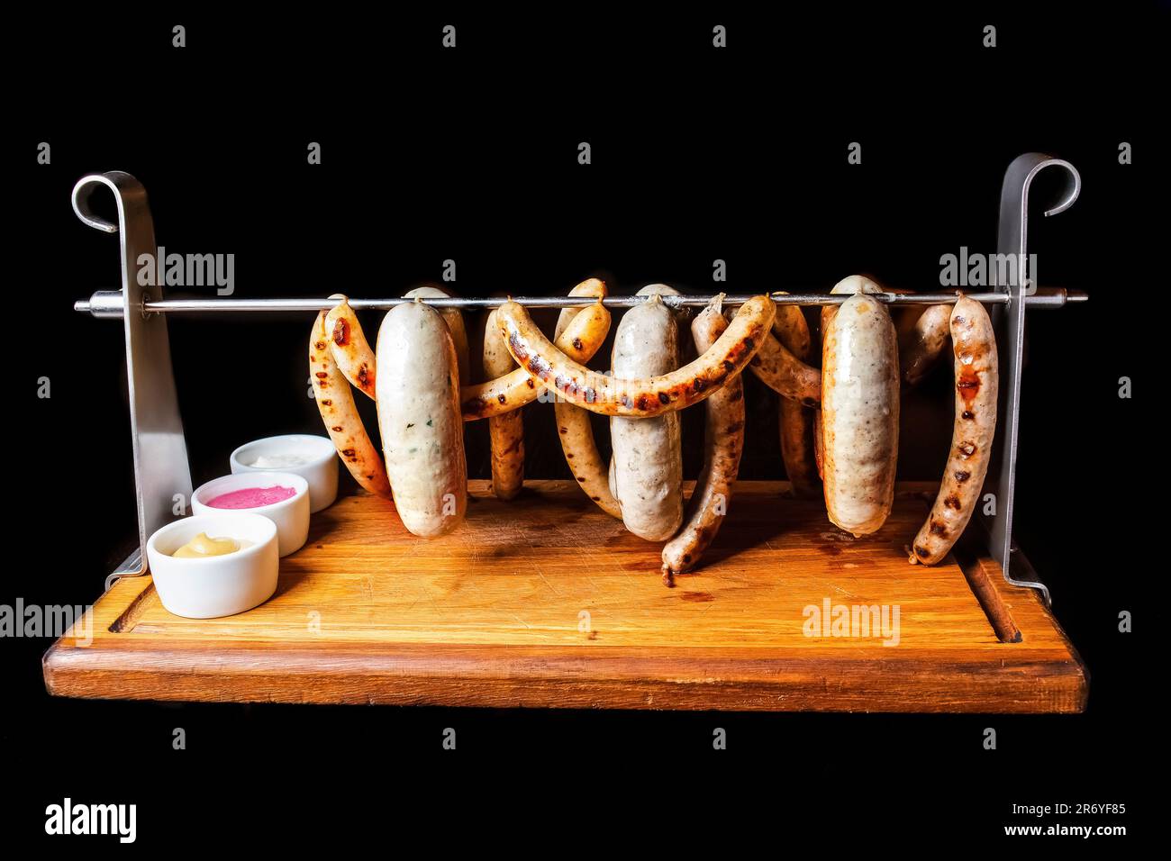 A studio shot of fresh sausage on a skewer set against a black ...