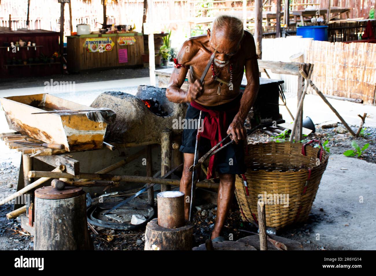 Thai oldman people blacksmith or metalsmith making ancient iron armor ...