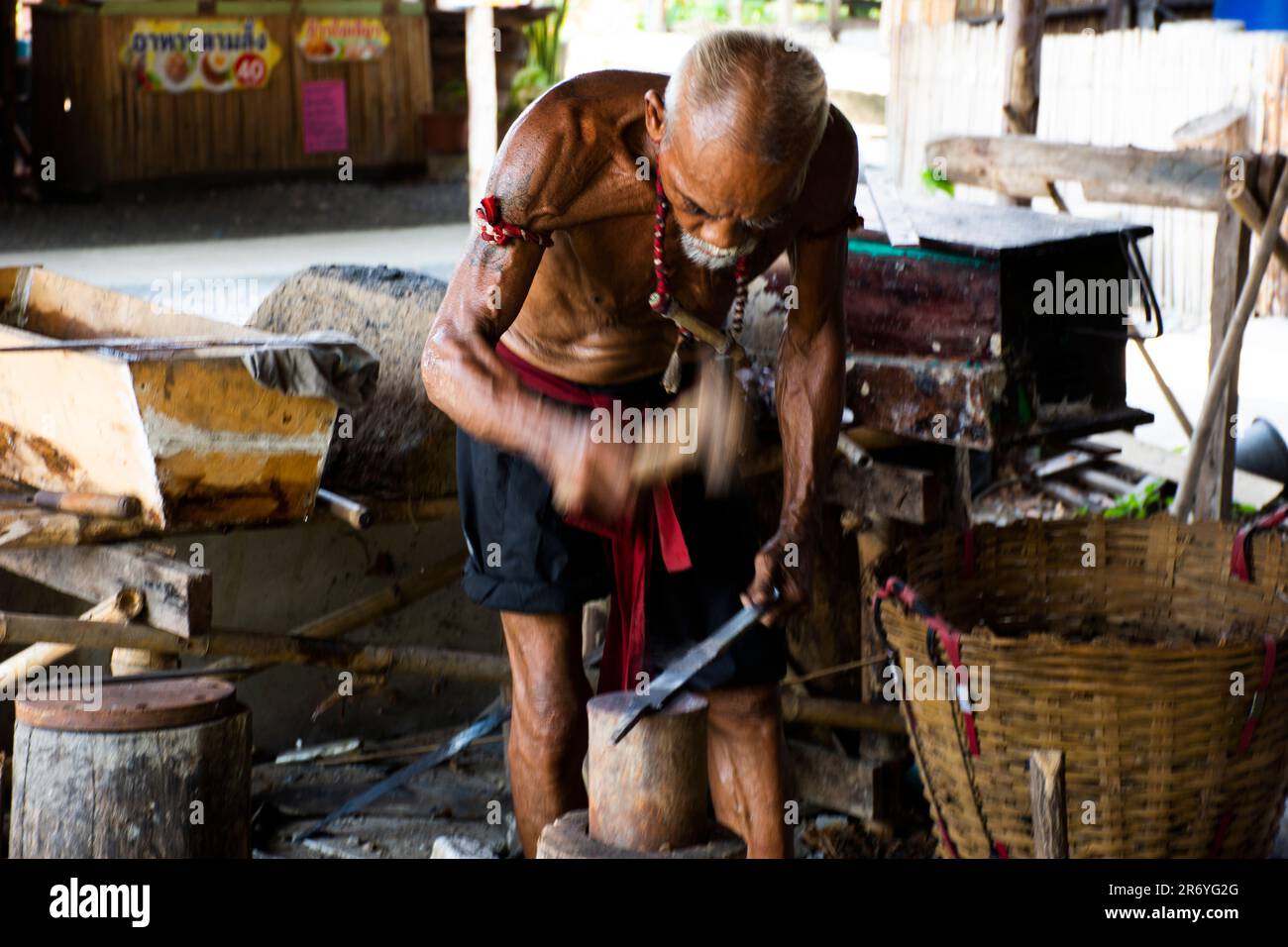 Thai oldman people blacksmith or metalsmith making ancient iron armor and steel metal antique ...