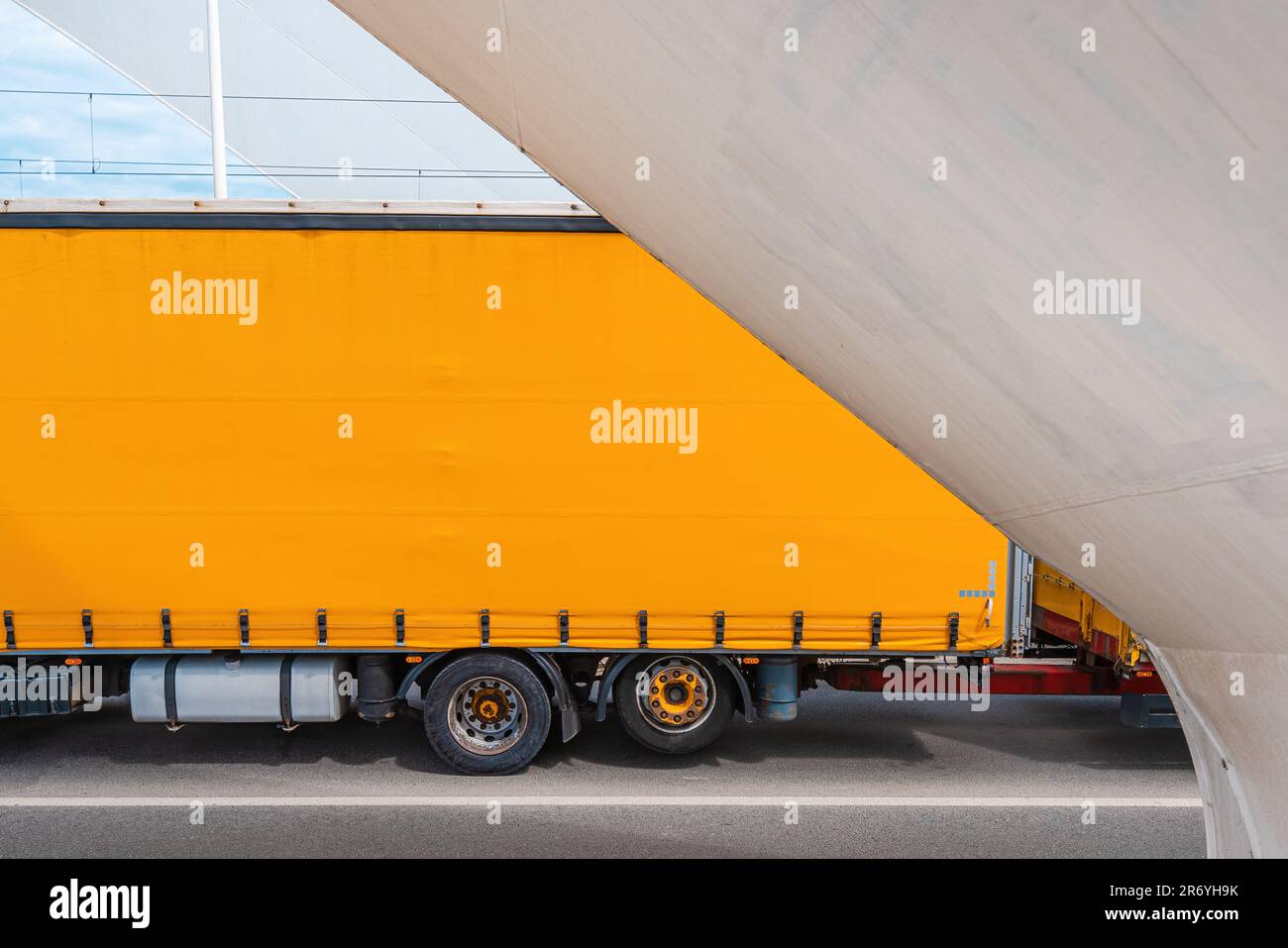 Yellow truck trailer on the road, semi-truck eighteen wheeler crossing ...
