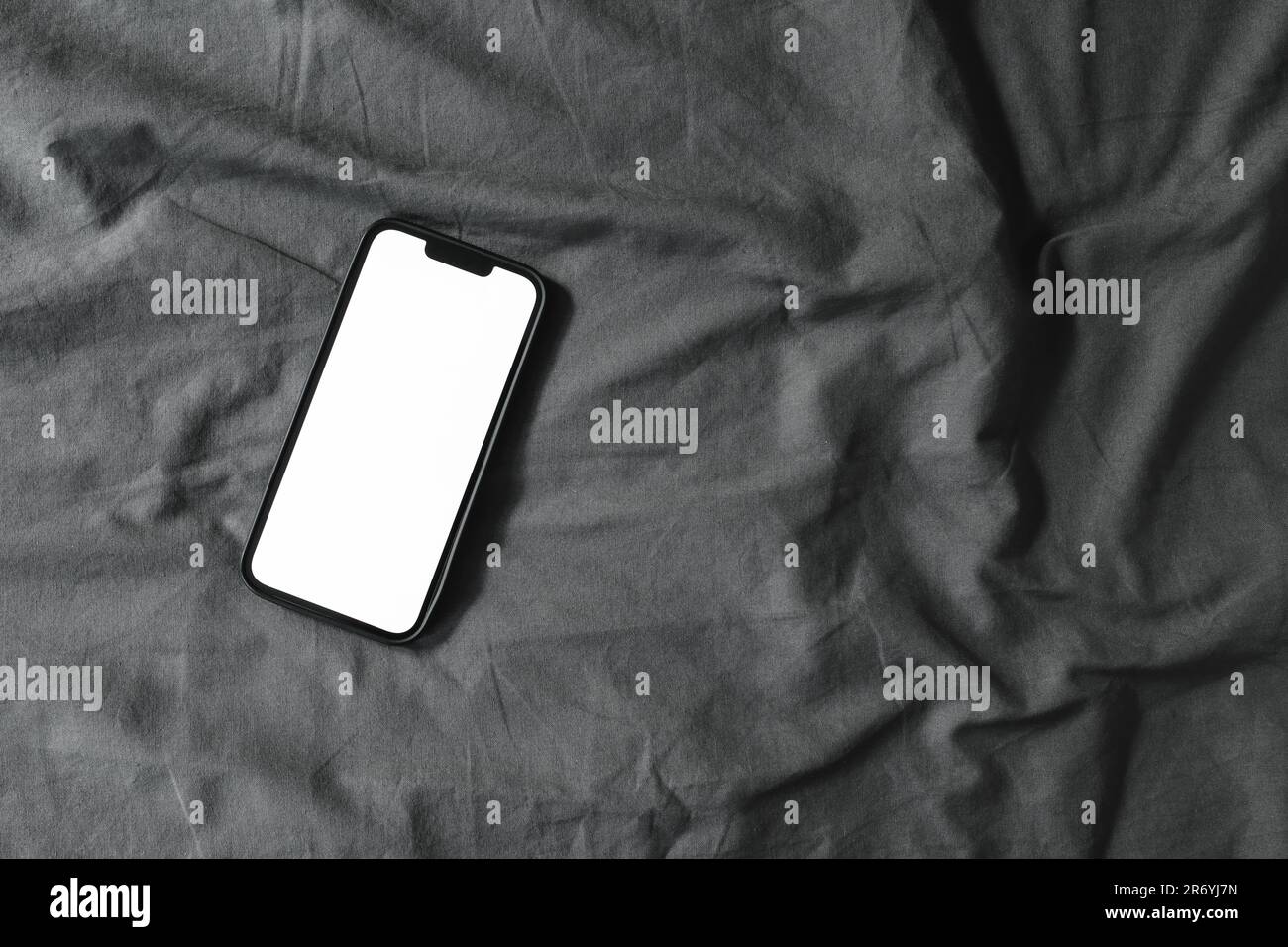 Smart mobile phone with blank mockup screen on wrinkled bed linen, top ...