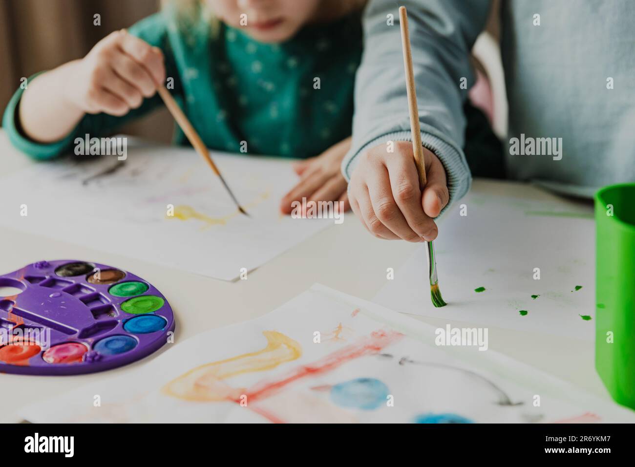 Two cute little sisters, classmates are painting on table. Small ...