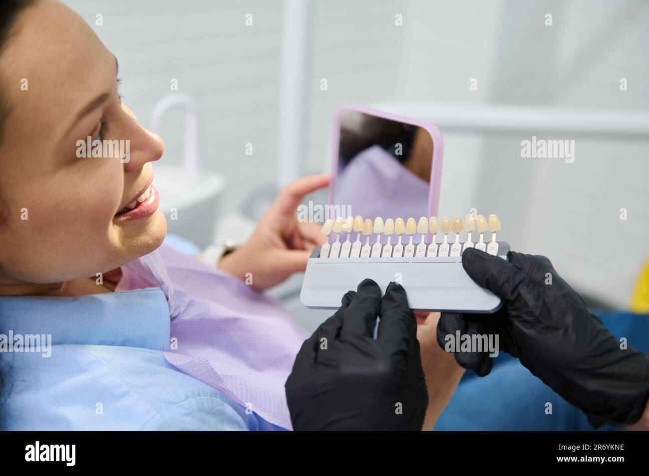 Smiling female patient receives dental care, teeth bleaching. Dentist ...