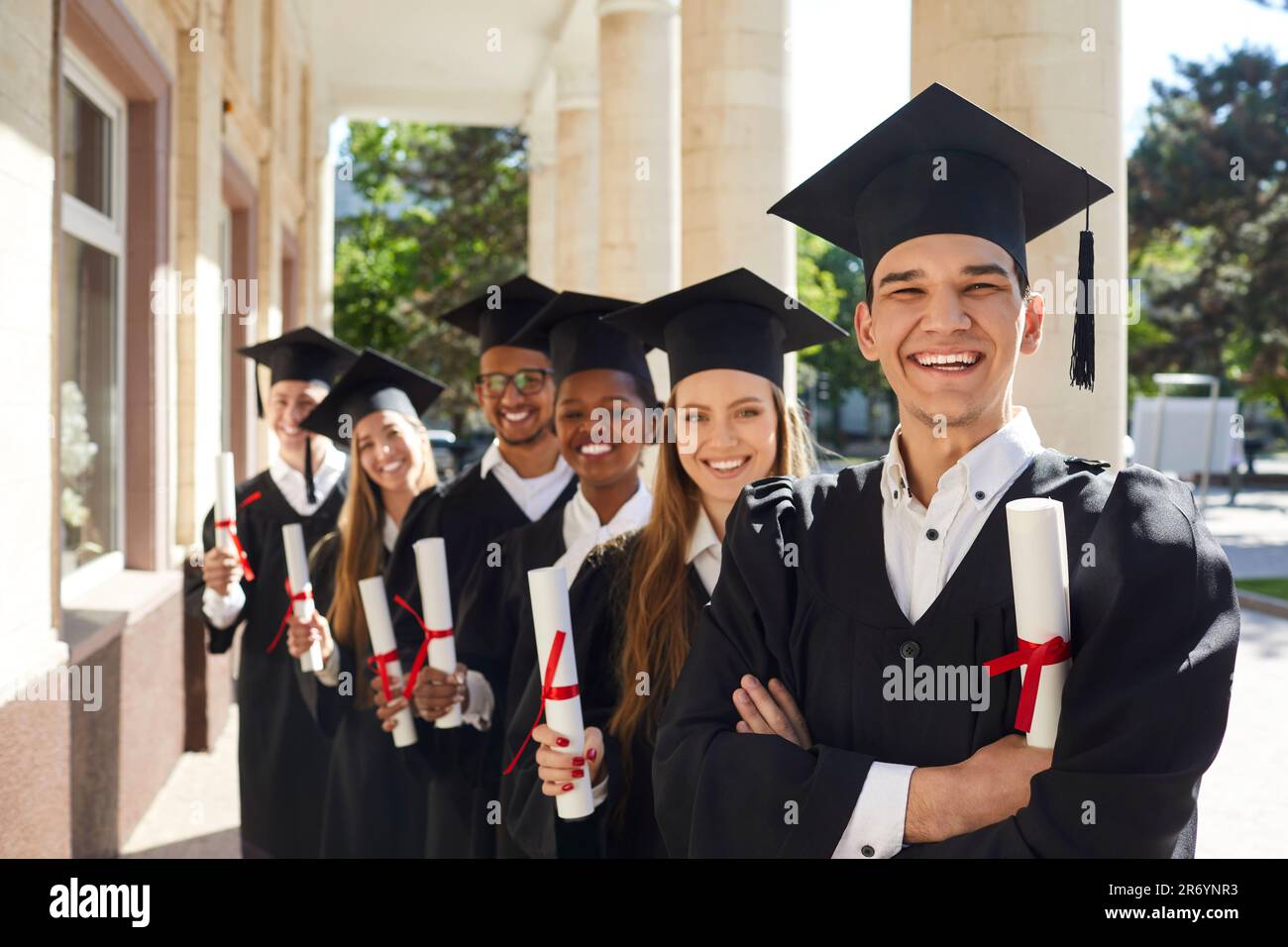 Photo of smiling college graduates standing behind each other Stock ...