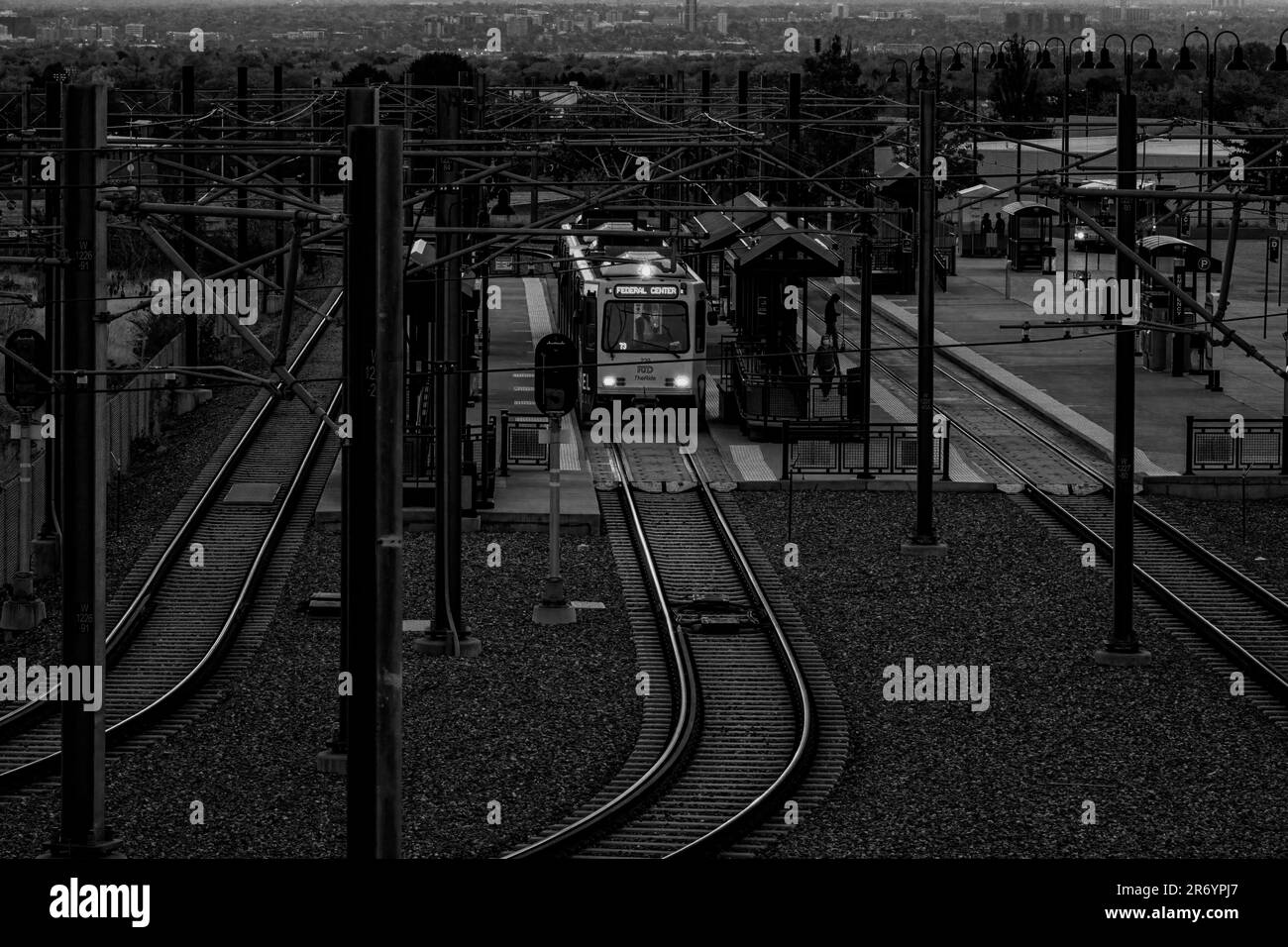 A grayscale shot of a passenger train curving around a bend in a large ...