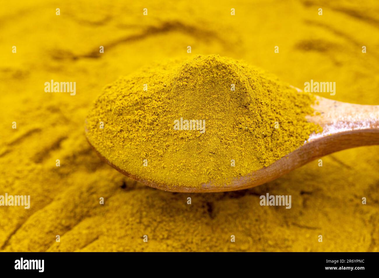 Powdered curry on wooden spoon. Pile of curry powder. close up Stock ...