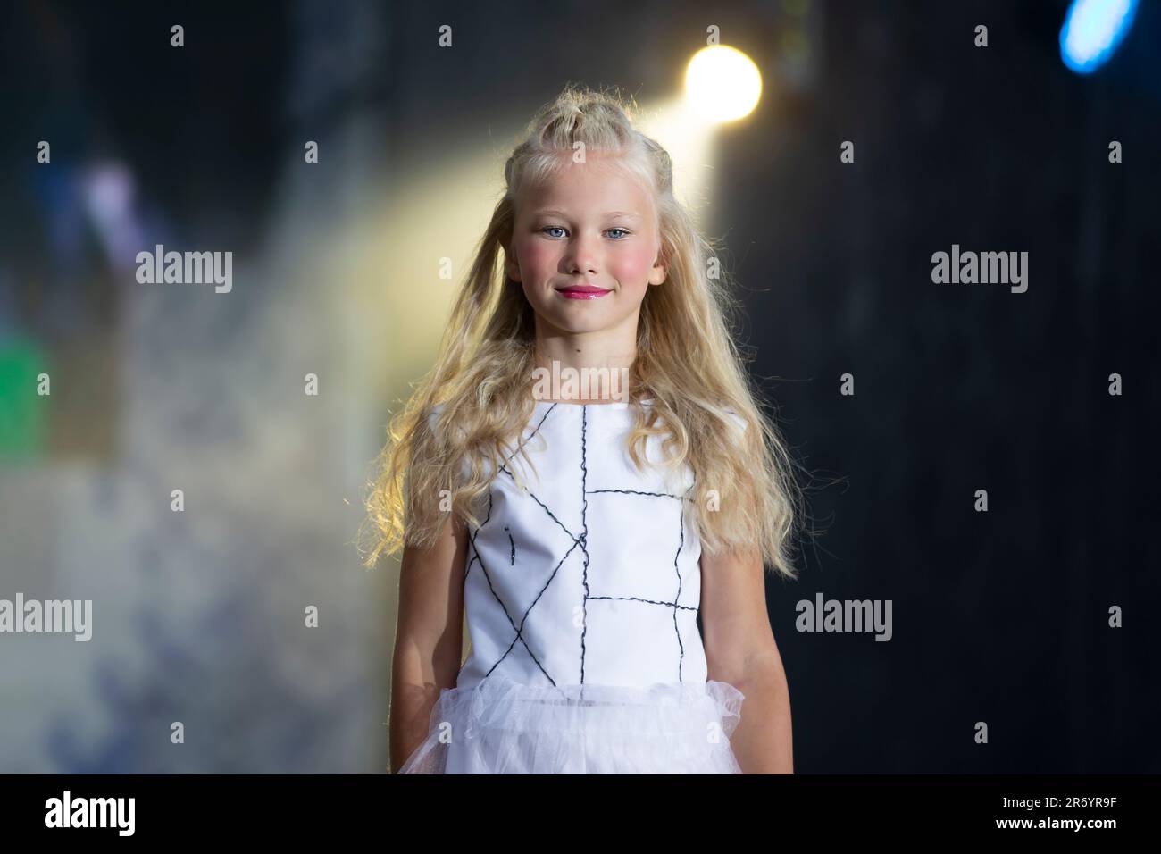 Blond little girl model on stage light background Stock Photo - Alamy