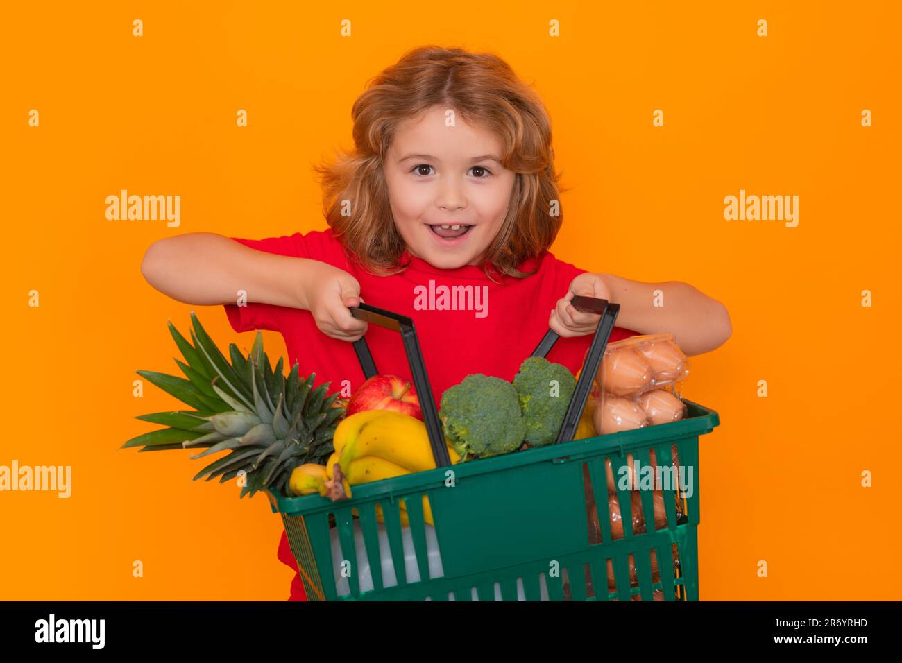 Portrait of child with shopping basket purchasing food in a grocery ...