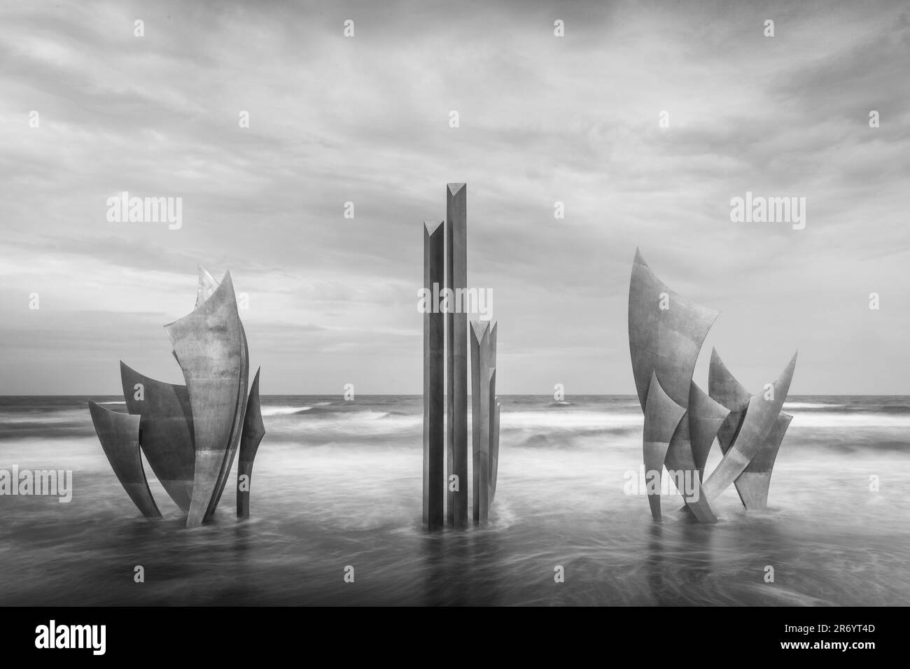 Three abstract metal sculptures stand in a tranquil aquatic landscape ...