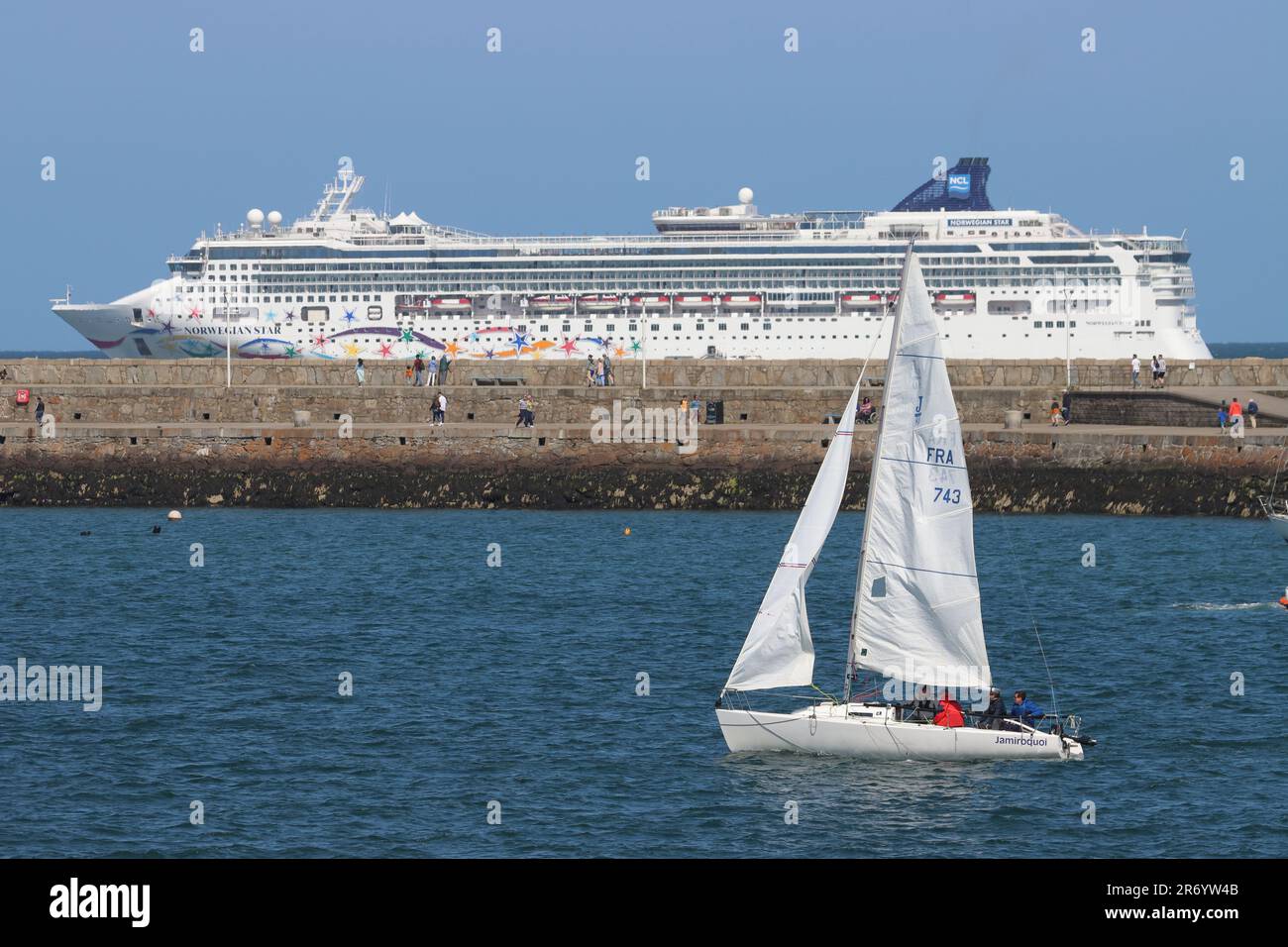 Yacht inside harbour wall, with MS Norweigan Star moored offshore in ...