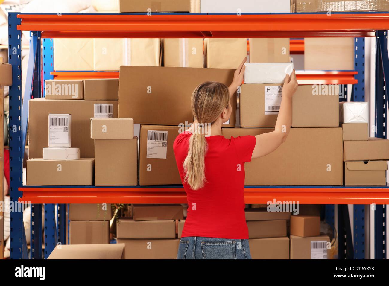 Post office worker taking parcel from rack indoors, back view Stock ...