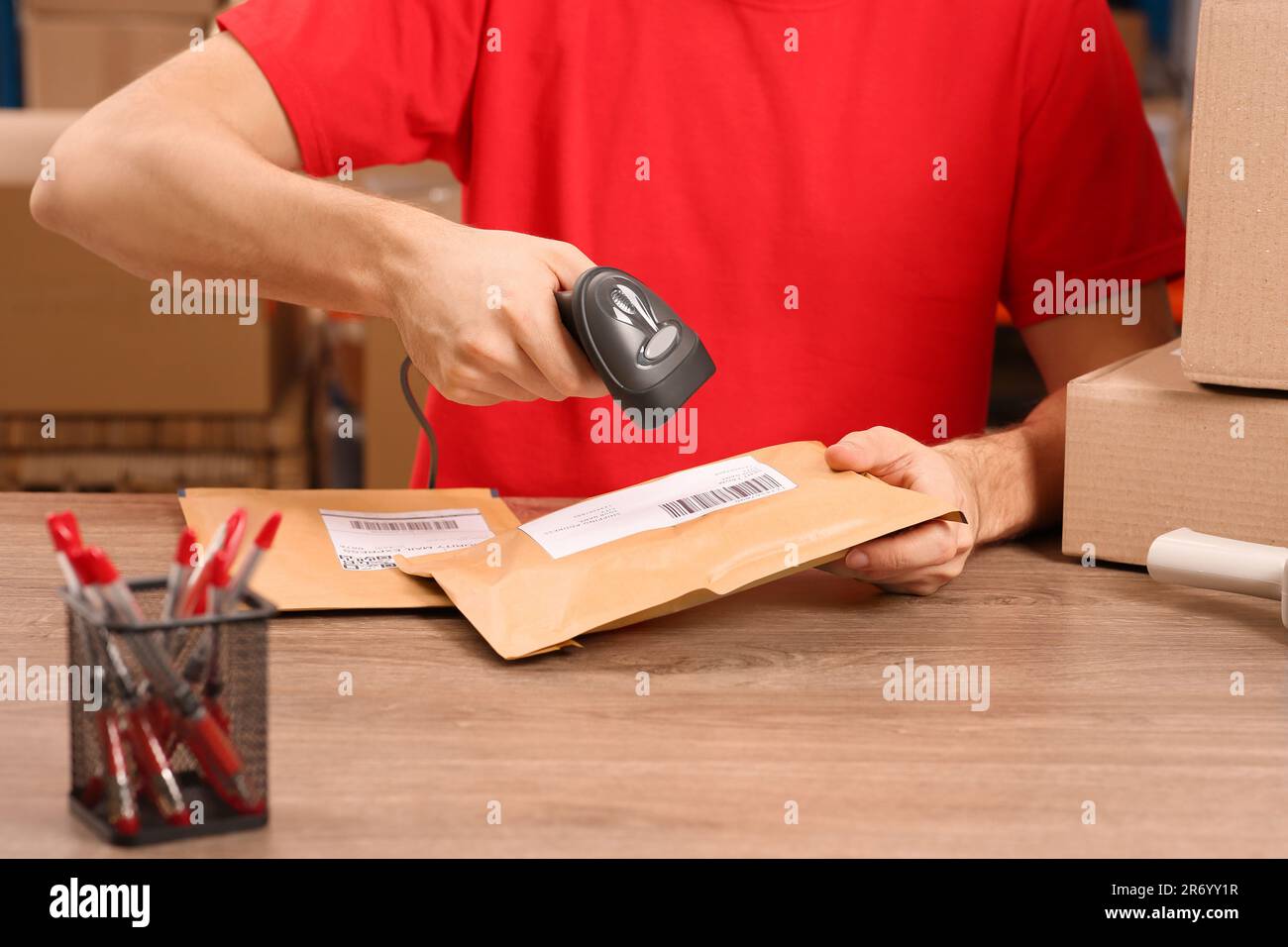 Post office worker with scanner reading parcel barcode at counter ...