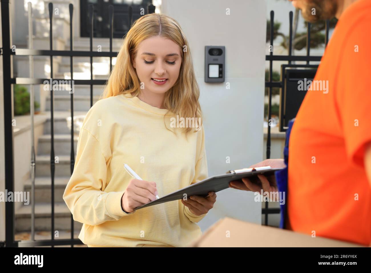 Woman signing order receipt outdoors. Courier delivery Stock Photo - Alamy