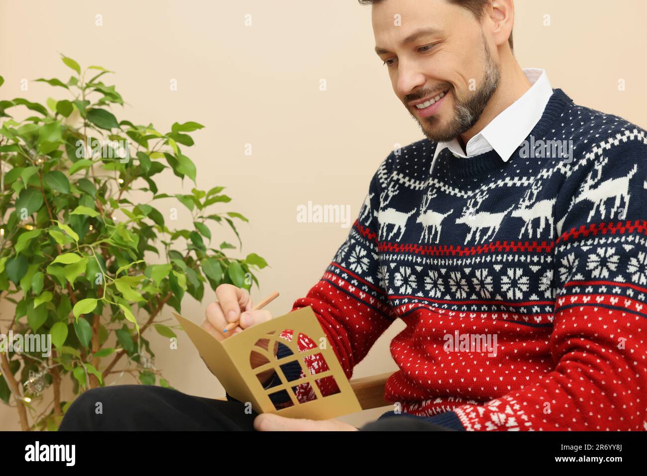 Happy man writing wishes in greeting card in living room Stock Photo ...