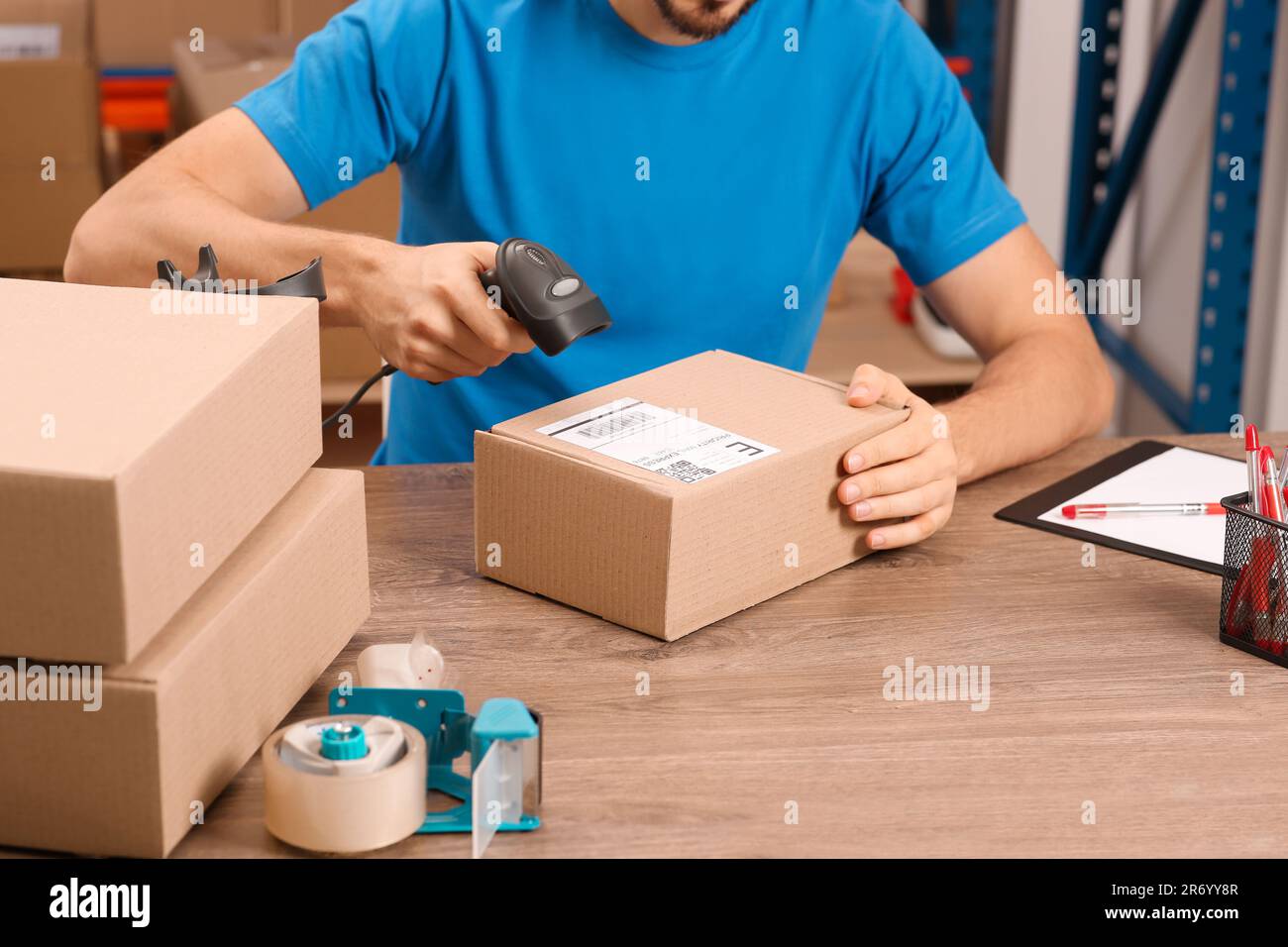Post office worker with scanner reading parcel barcode at counter ...