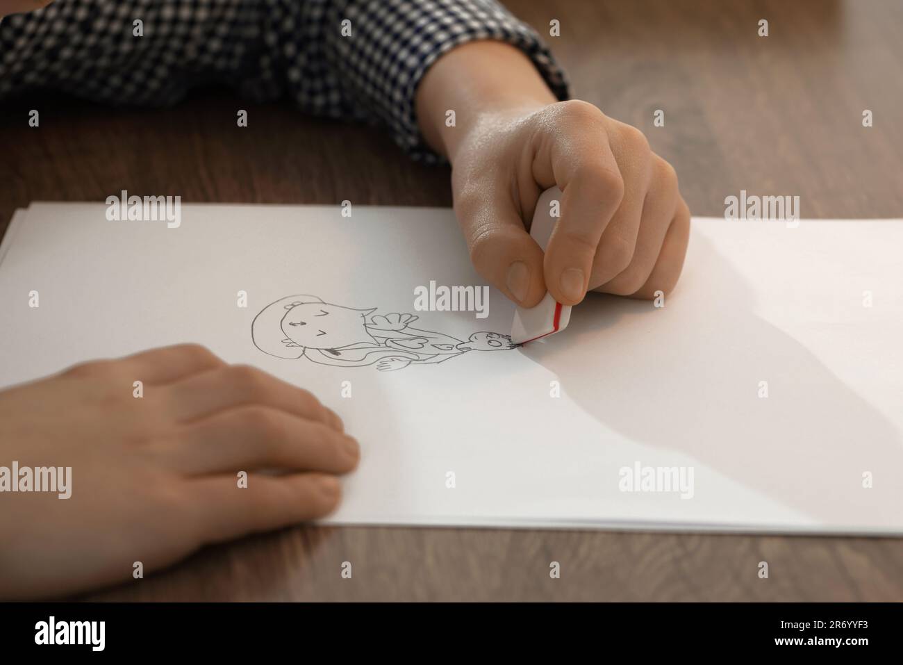 Boy erasing mistake in his notebook at wooden desk, closeup Stock Photo ...