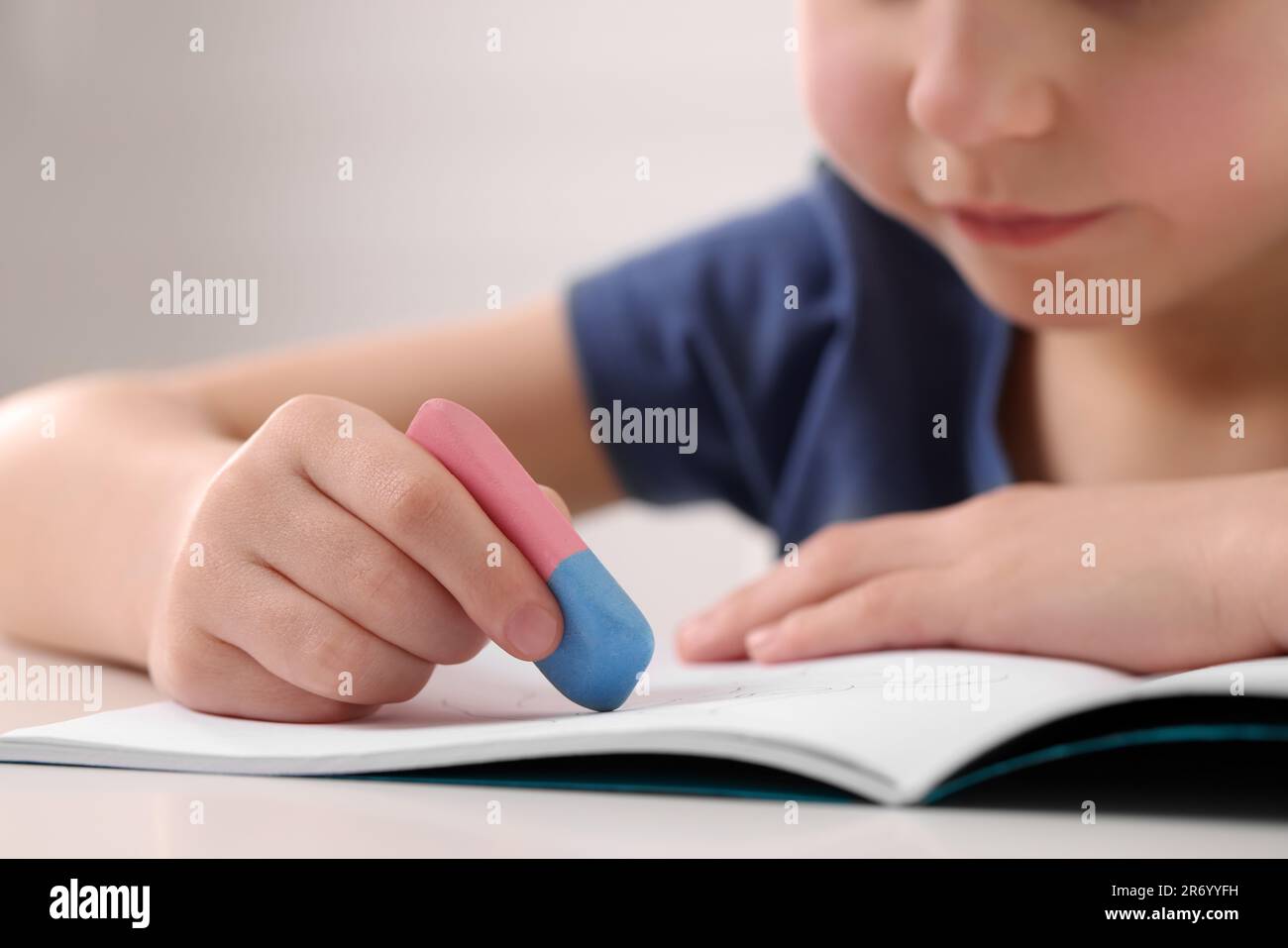 Little boy erasing mistake in his notebook at white desk, closeup Stock ...