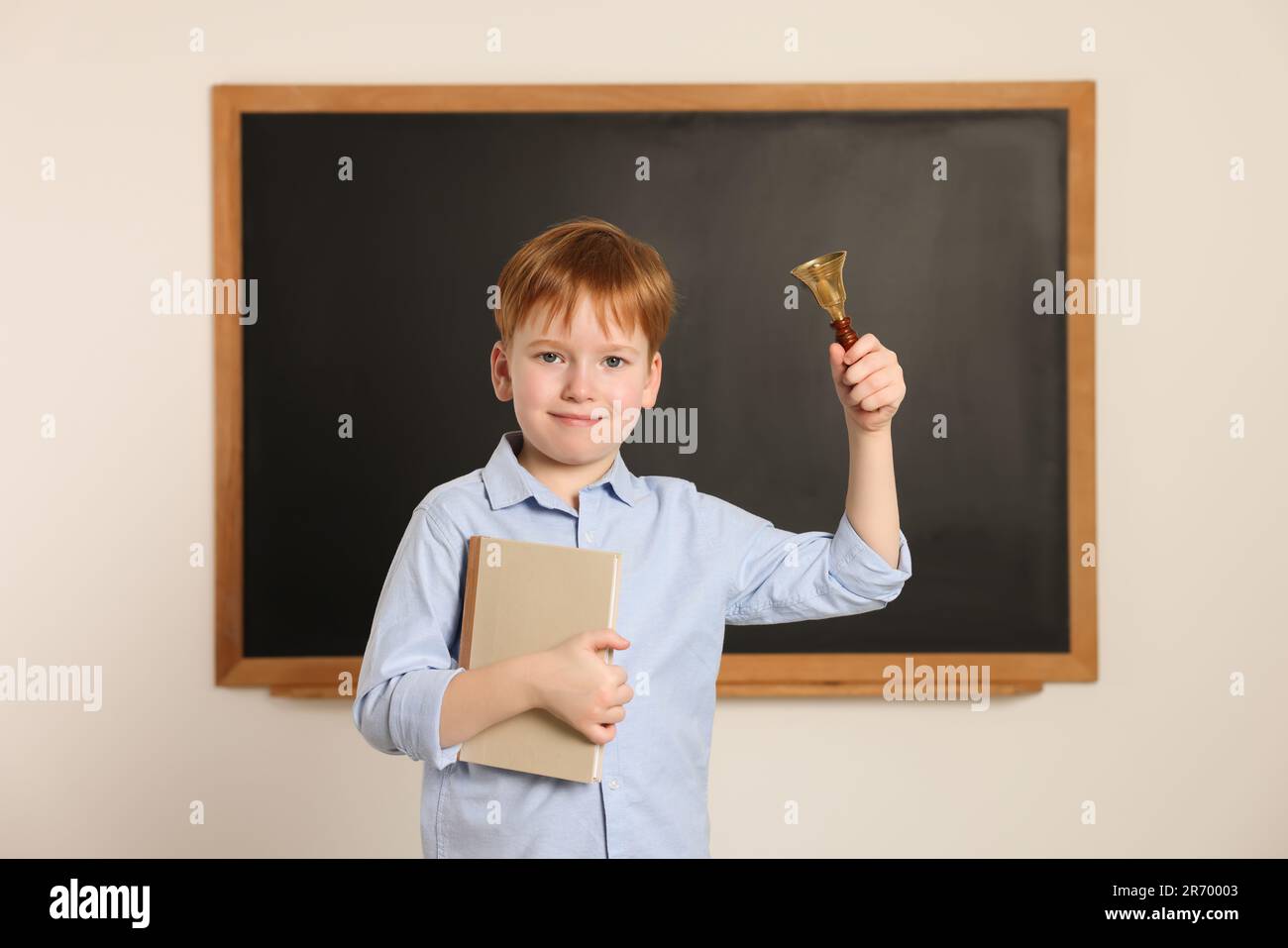 Cute little boy ringing school bell in classroom Stock Photo - Alamy