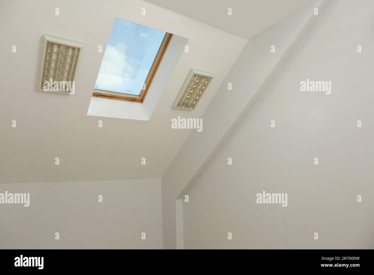 Skylight roof window on slanted ceiling in attic room, low angle view ...