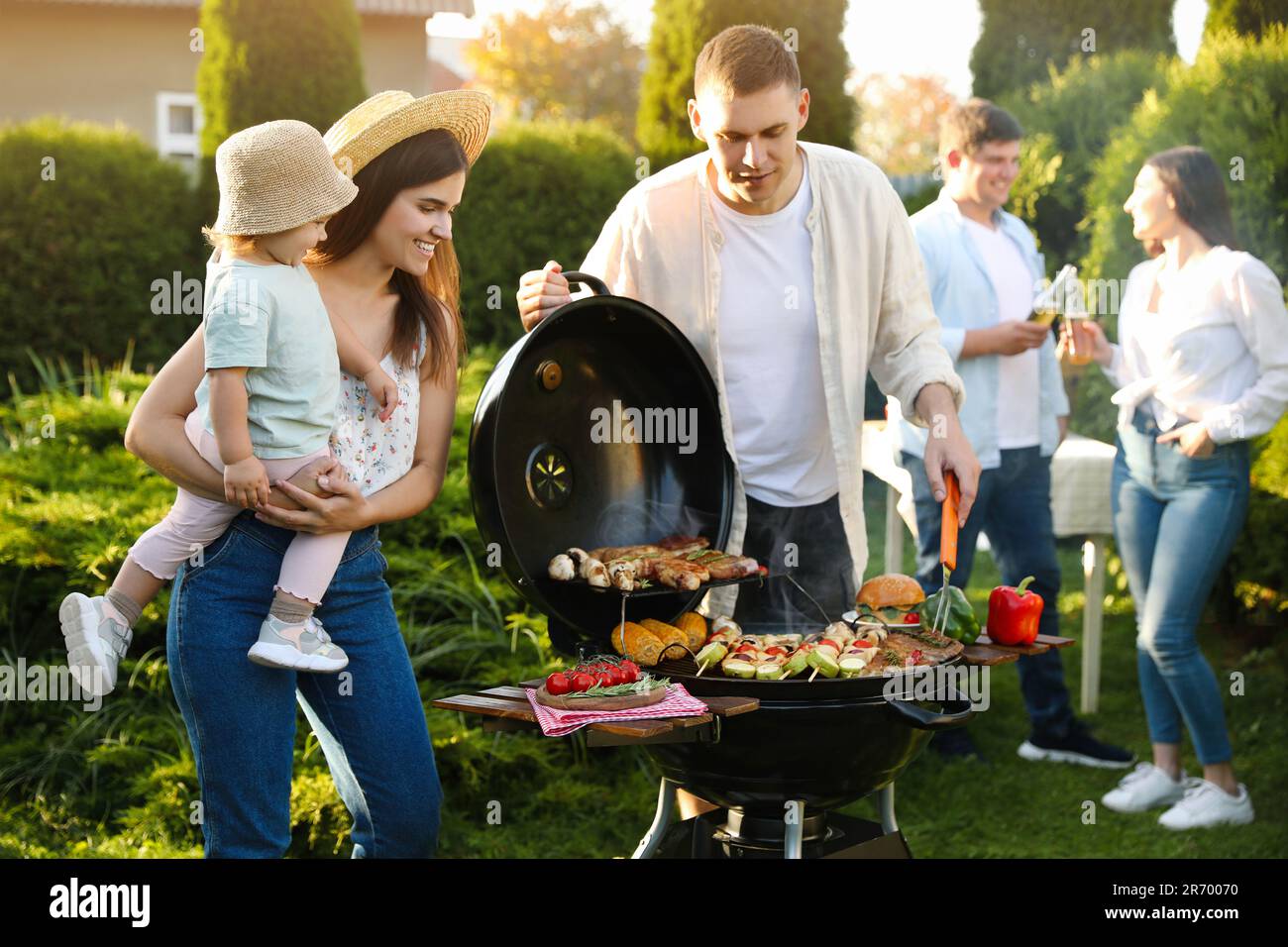 Family with friends having barbecue party outdoors Stock Photo - Alamy