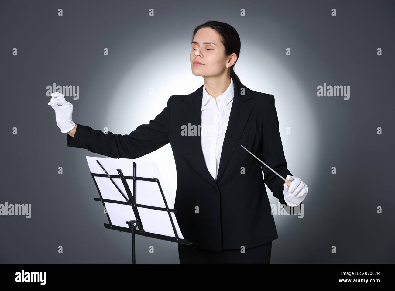 Professional conductor with baton and note stand on grey background ...