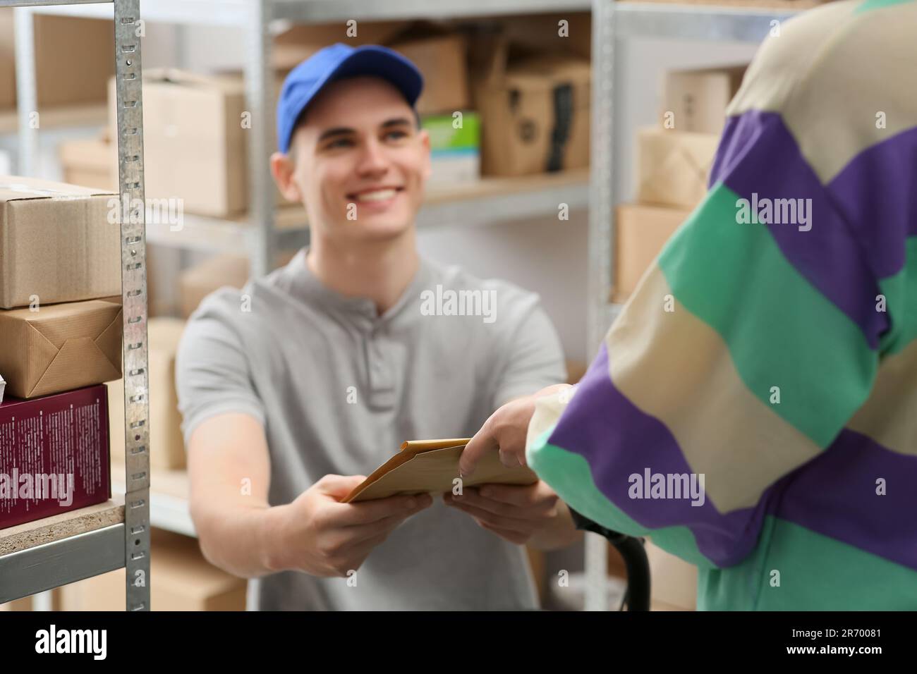 Worker giving parcel to woman at post office Stock Photo - Alamy