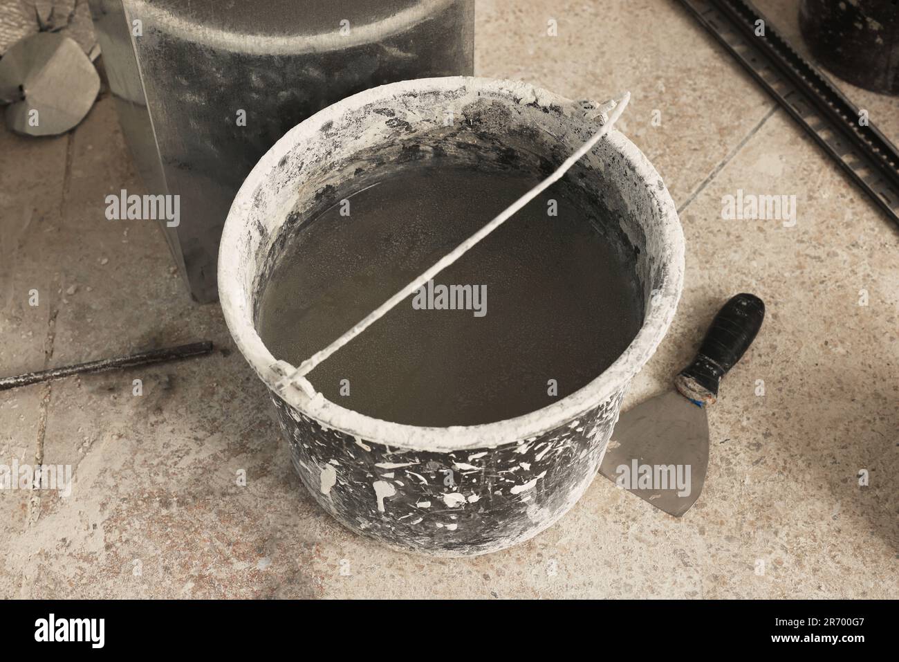 Bucket of adhesive mix and spatula on floor indoors Tiles installation ...
