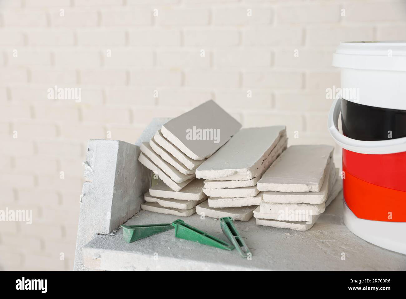 Bucket with cement, tile spacers and many white decorative bricks in ...