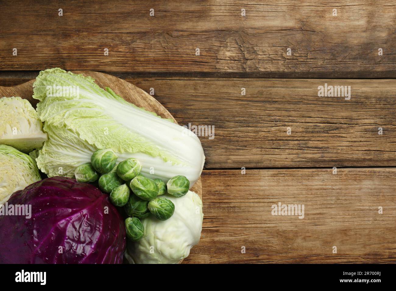 Different types of cabbage on wooden table, top view. Space for text ...