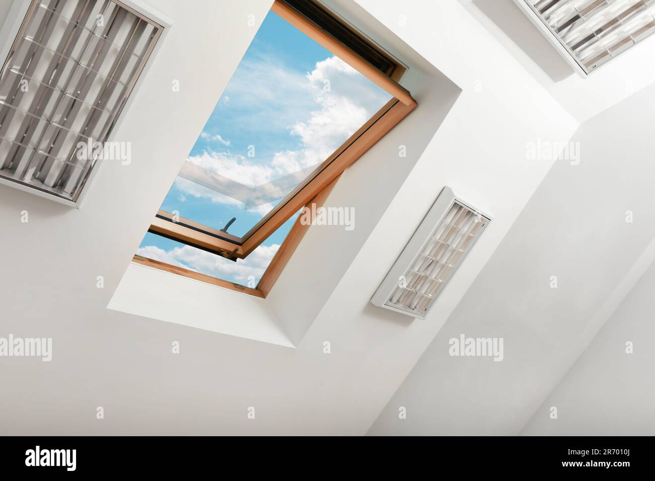 Open skylight roof window on slanted ceiling in attic room, low angle ...