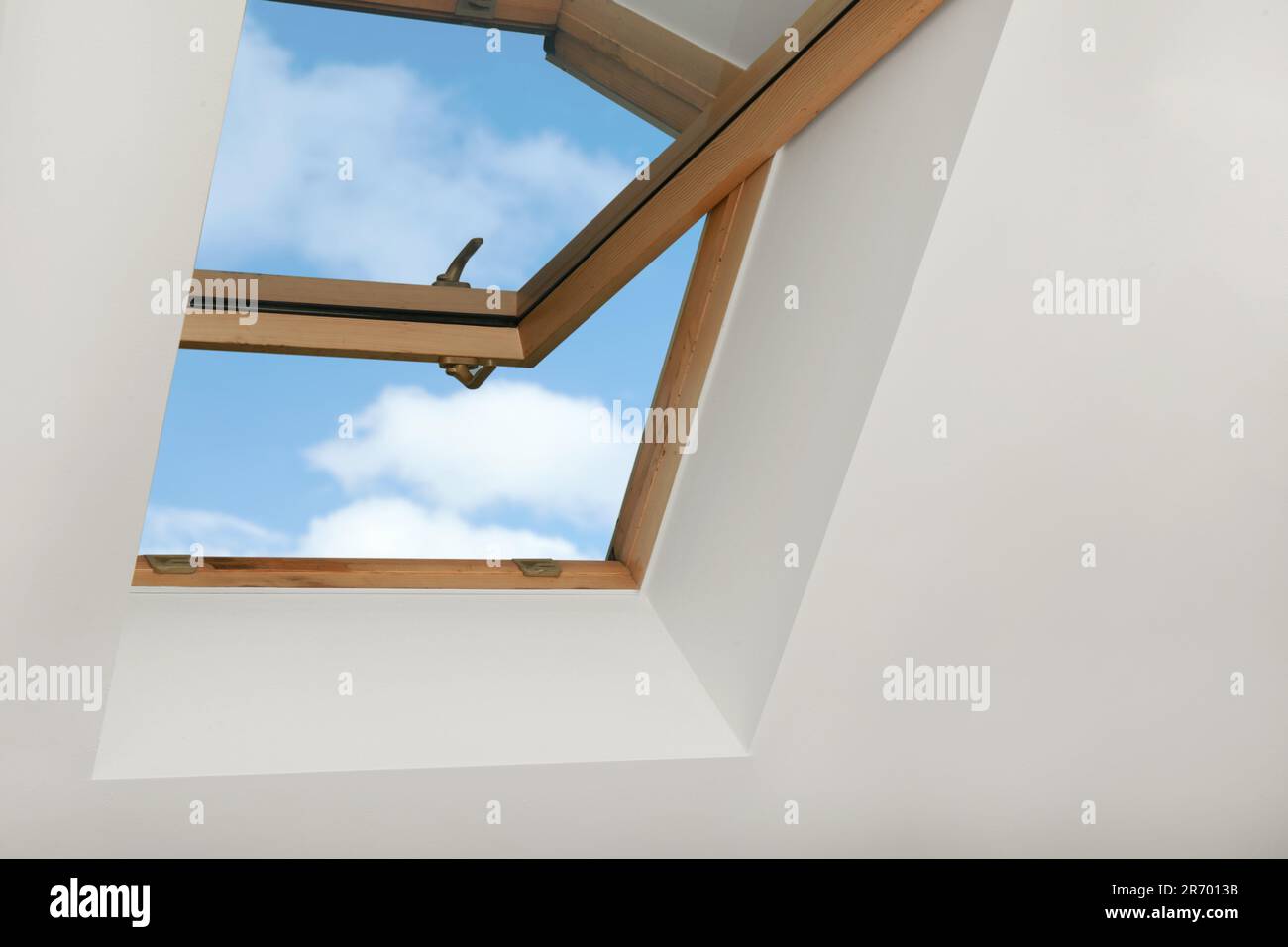 Open skylight roof window on slanted ceiling in attic room, low angle ...