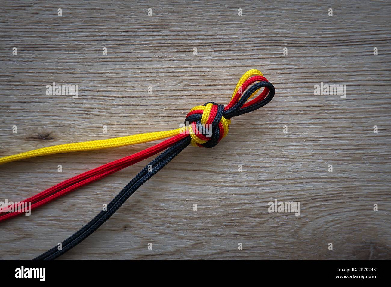 A vibrant image of two pieces of red, black, and yellow string tied ...