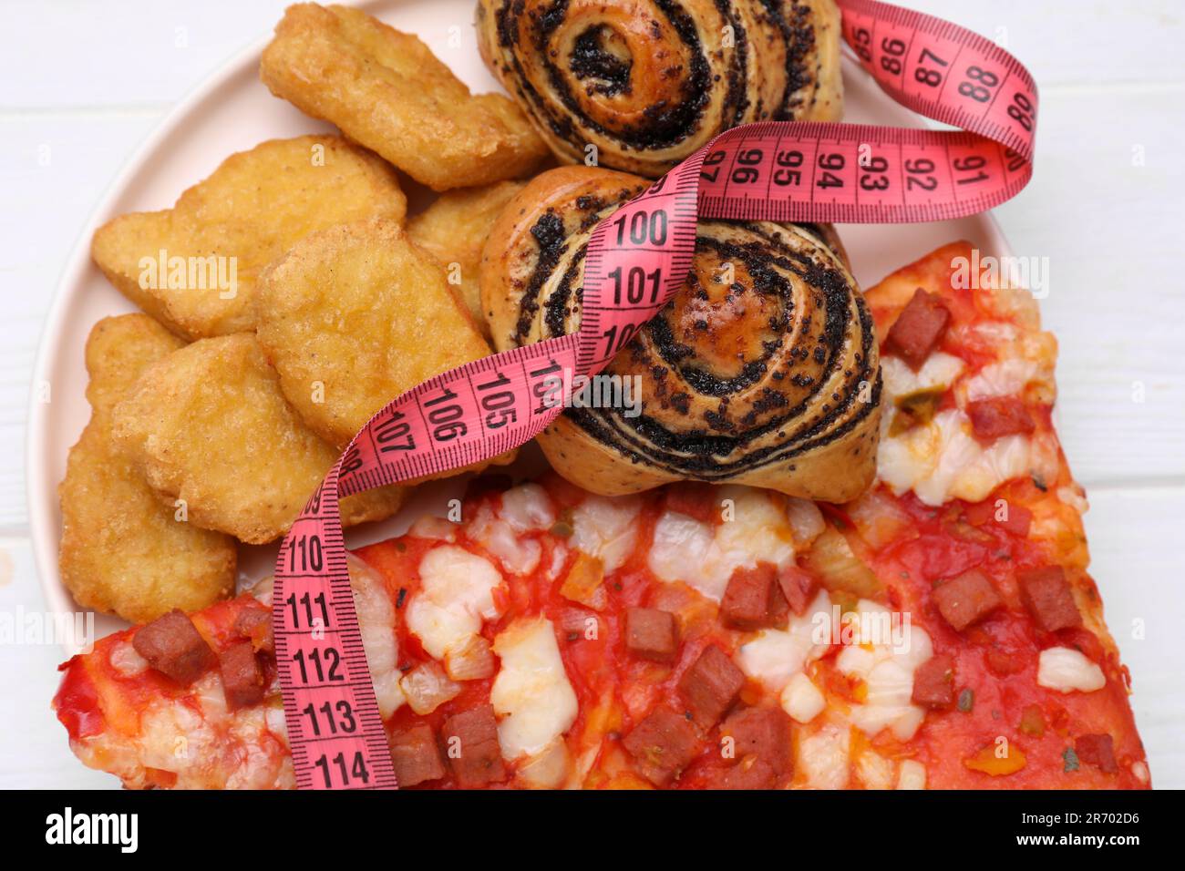 Different unhealthy food and measuring tape on white wooden table, top ...