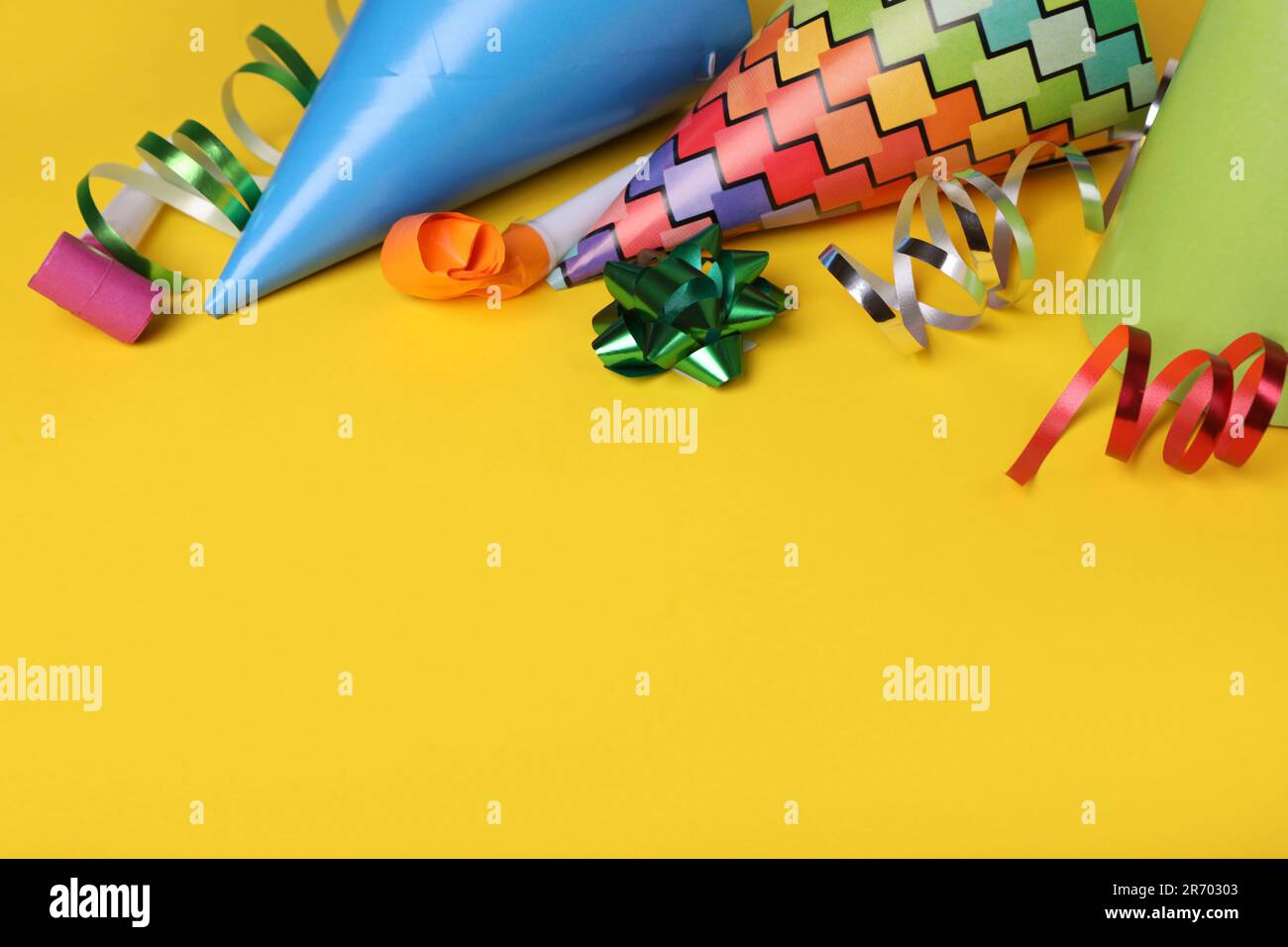 Party blowers, hats and streamers for birthday party on yellow ...
