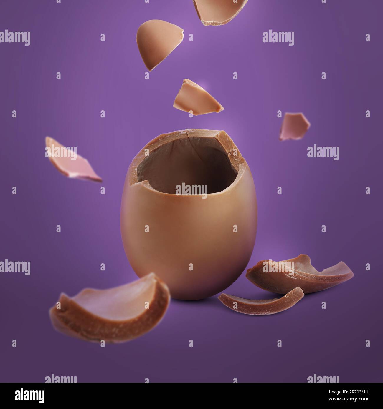 Exploded milk chocolate egg on purple background Stock Photo - Alamy