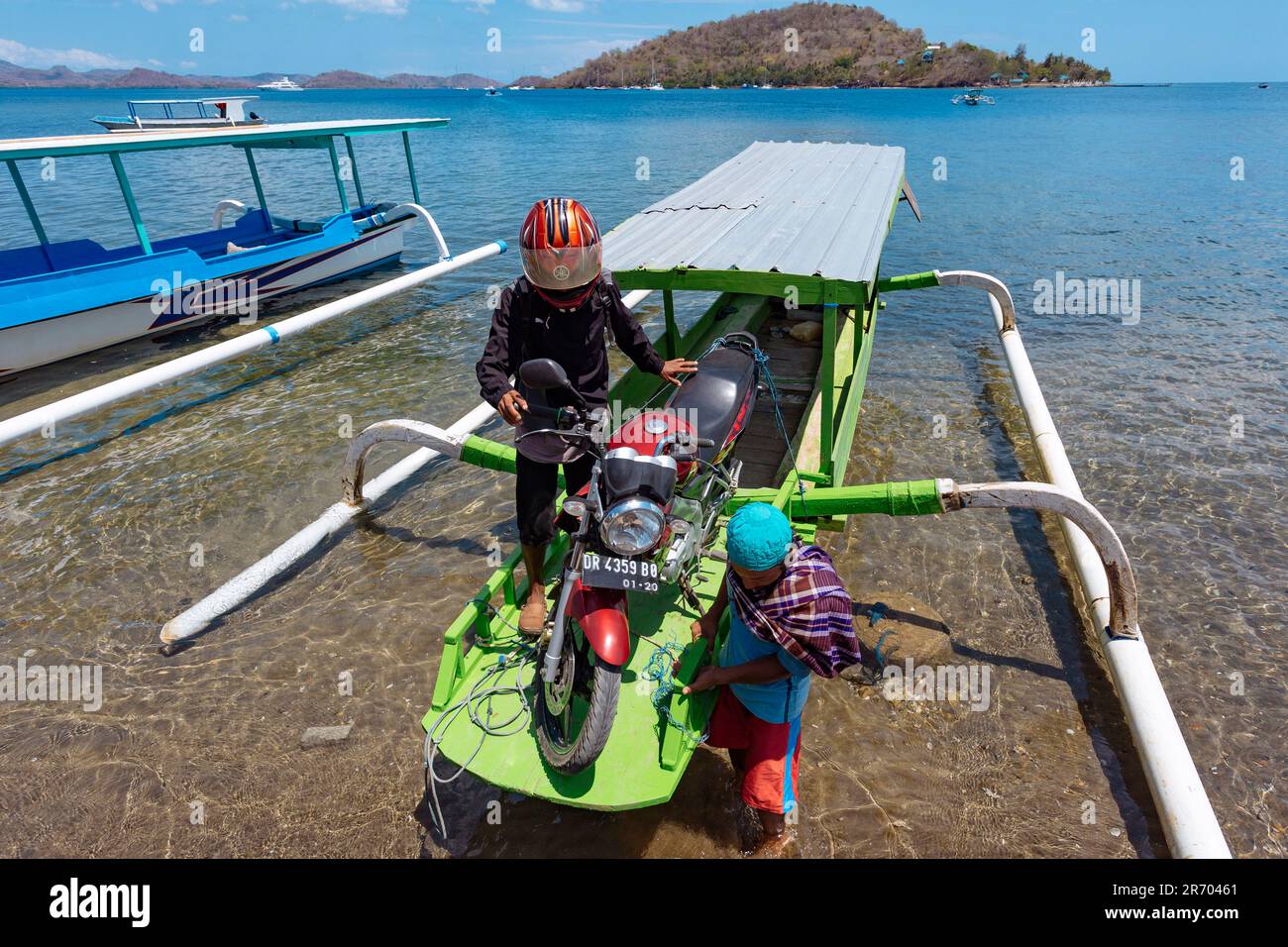 Two men with motorcycle on outrigger boat, Lembar, Lombok, Indonesia ...