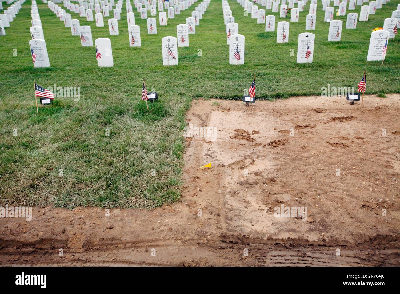Grass and gravestones border mud from newly dug graves at Section 60 in ...