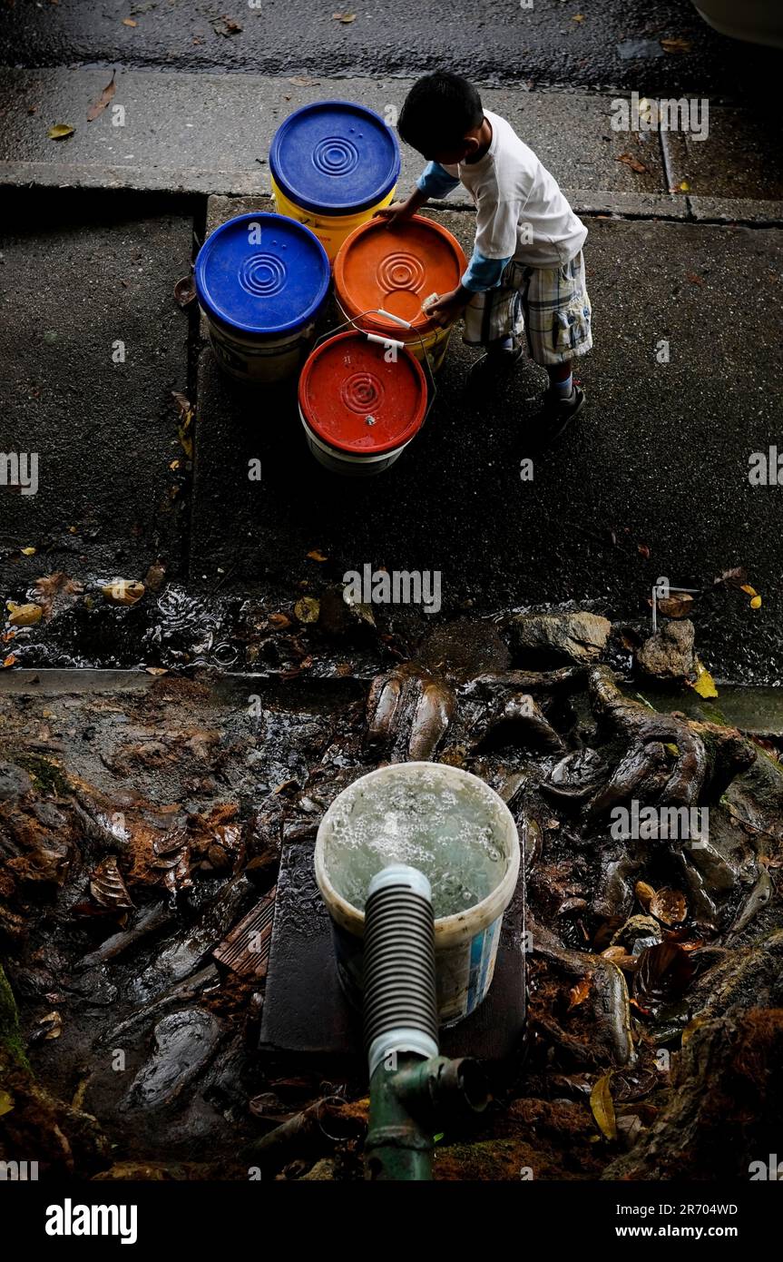 A child collects water in brightly colored buckets from a natural ...