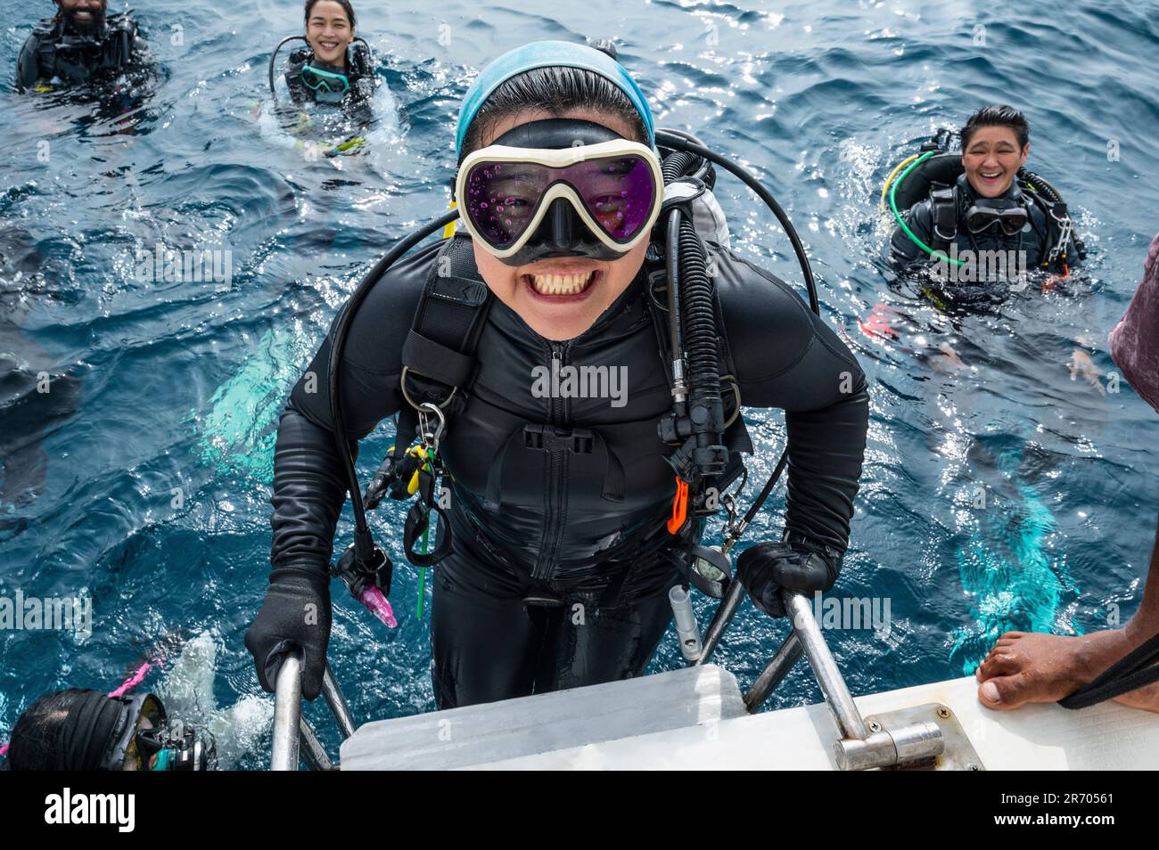 diver climbing up to a boat after finishing a dive in the Maldives ...