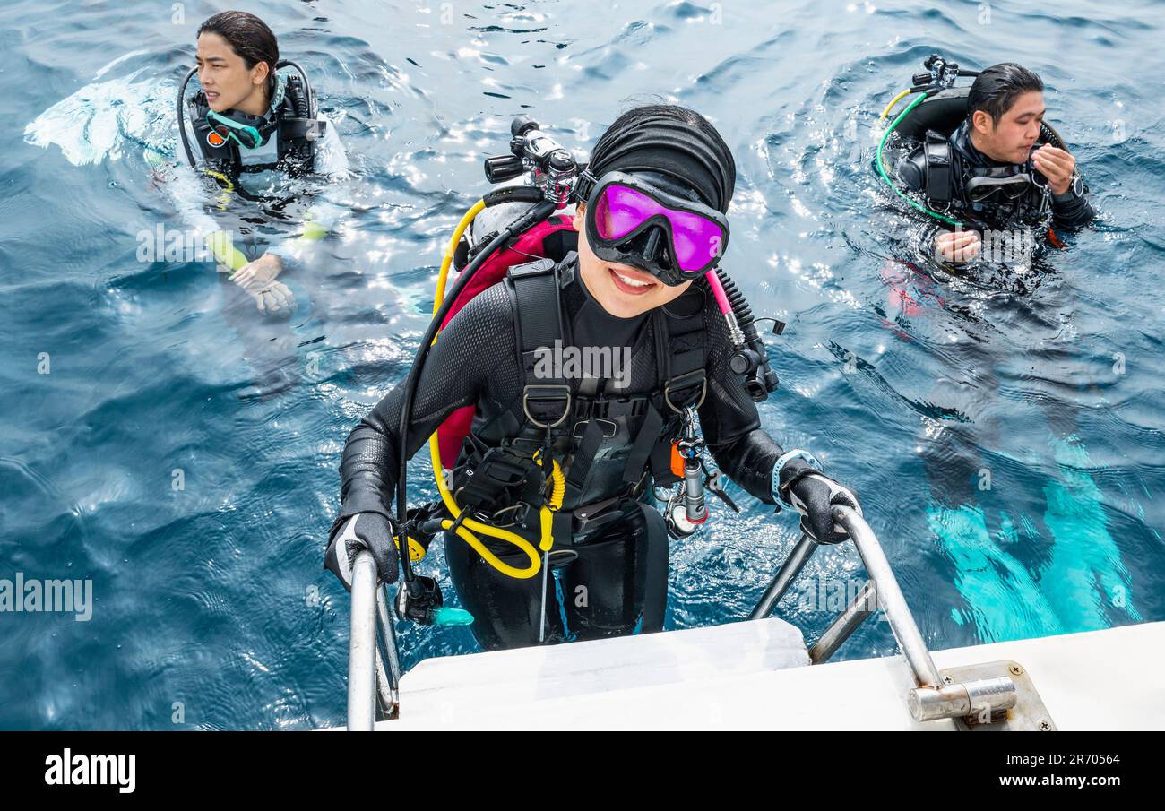 diver climbing up to a boat after finishing a dive in the Maldives ...